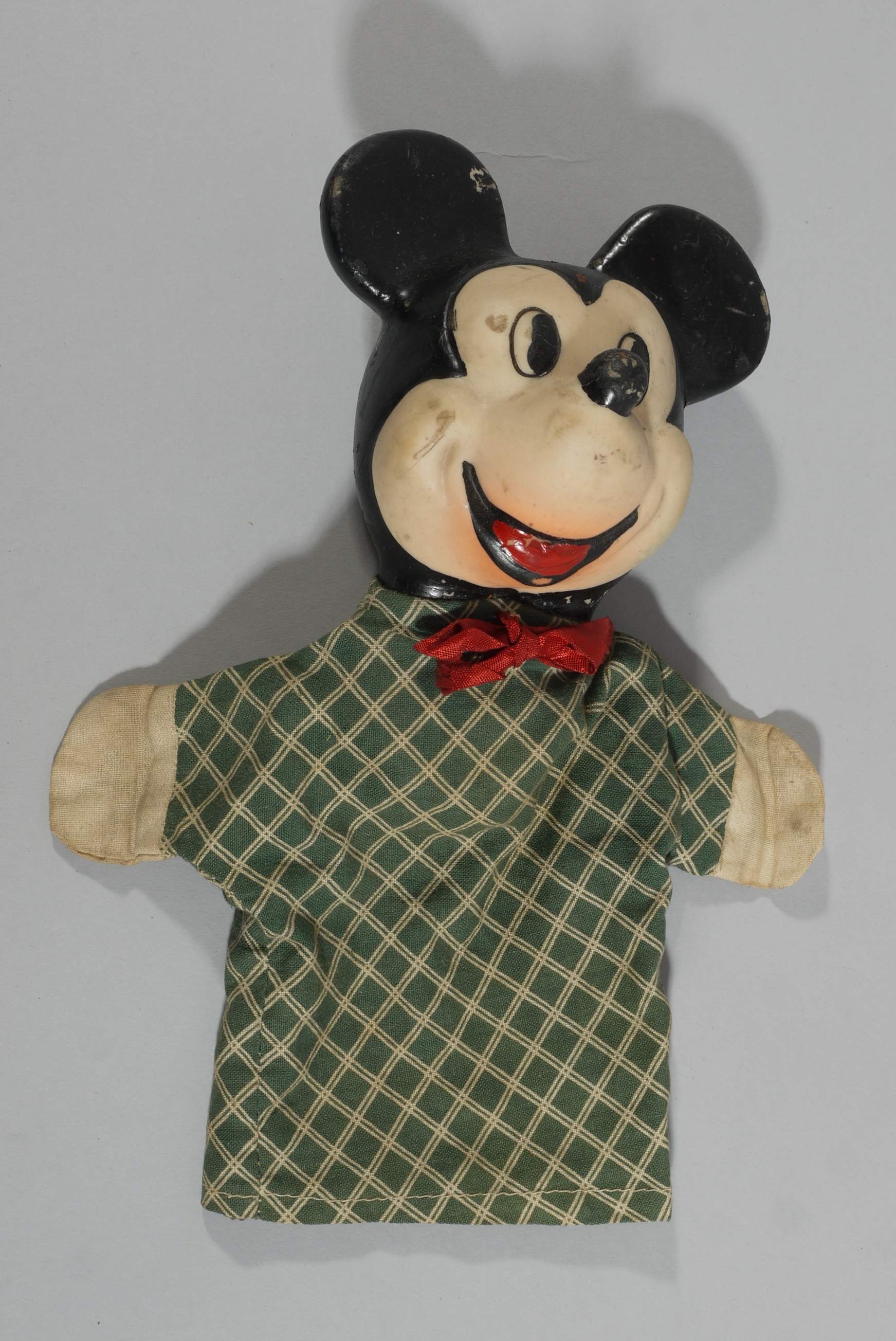 A painted rubber Mickey Mouse hand puppet with red fabric bow and green ...