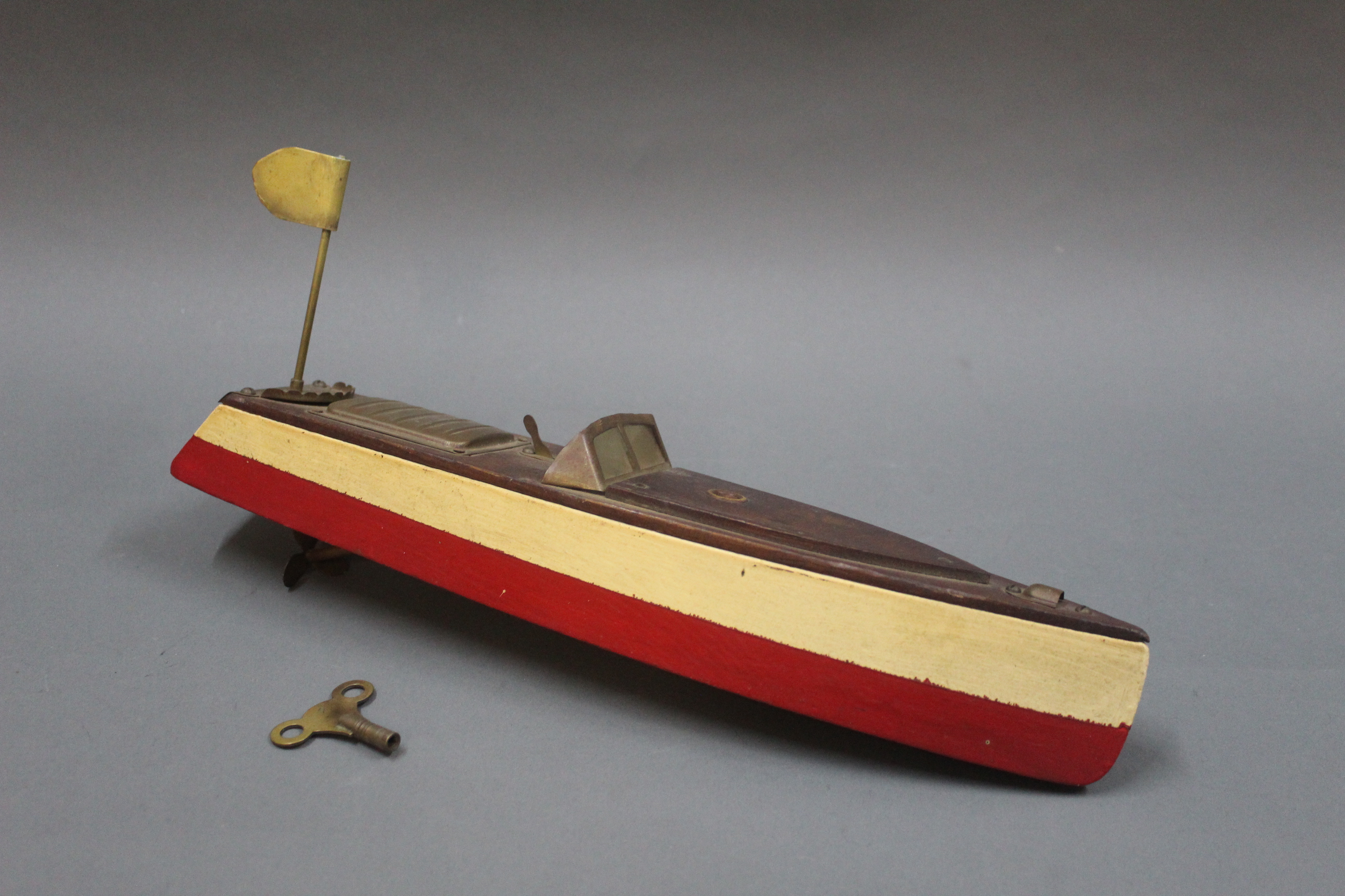 A painted wooden clockwork model boat, in red/cream, with key ...
