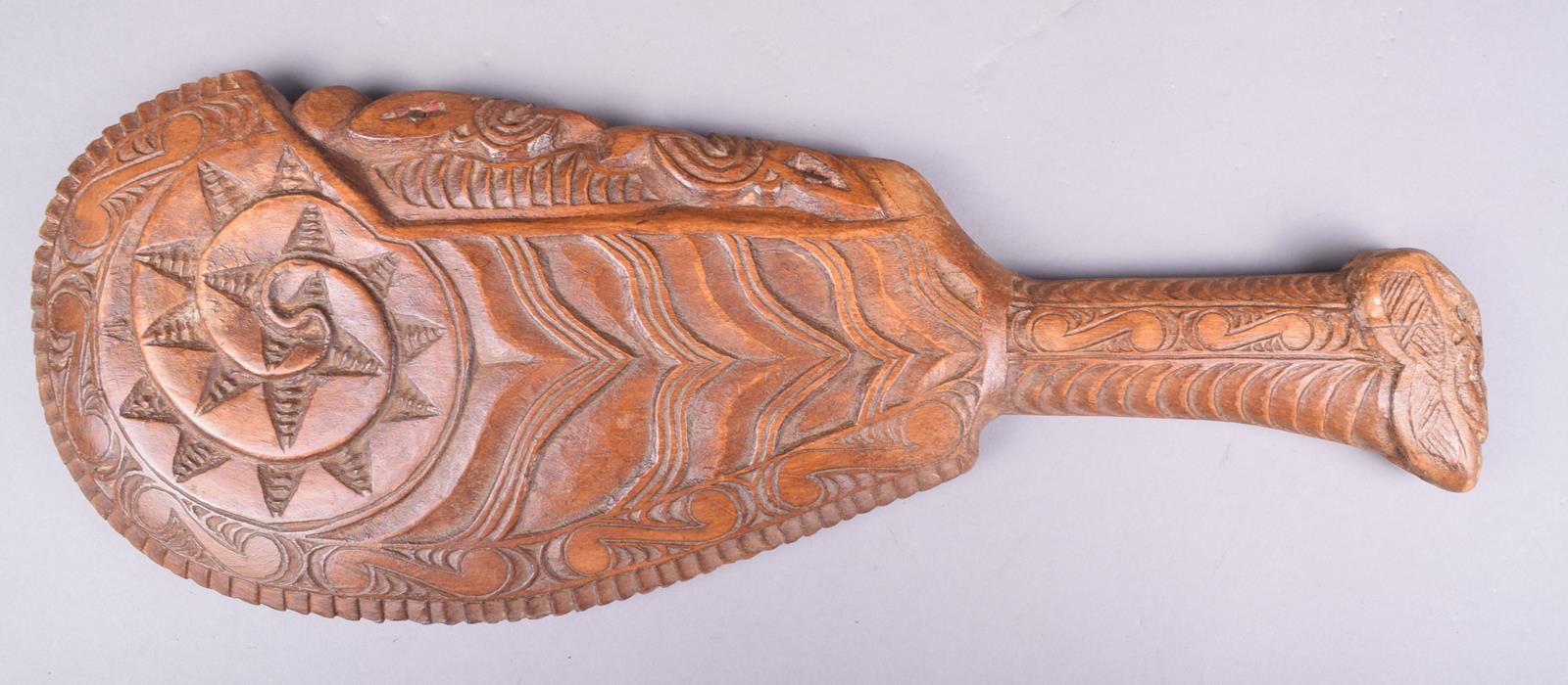 A Maori style wahaika, carved with tiki with applied shell eyes, 44cm long.