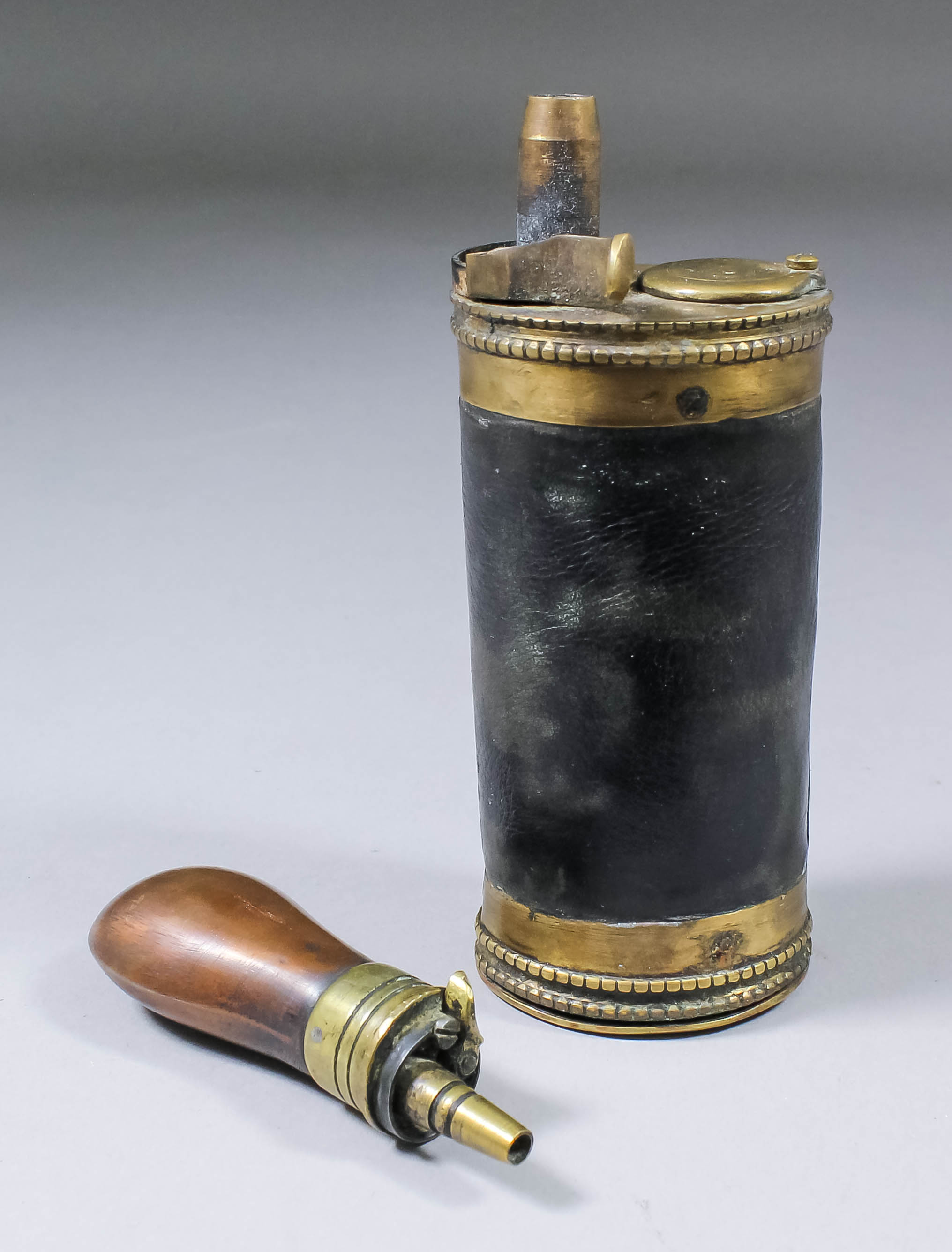 Two 19th Century powder flasks, comprising of one leather covered three ...