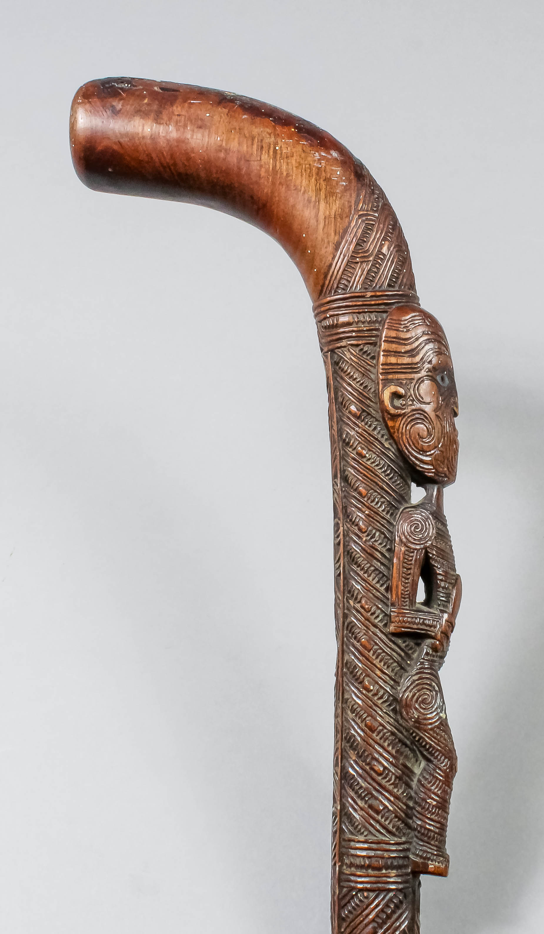 A Maori carved wood walking stick, carved with two Tiki figures, linear ...