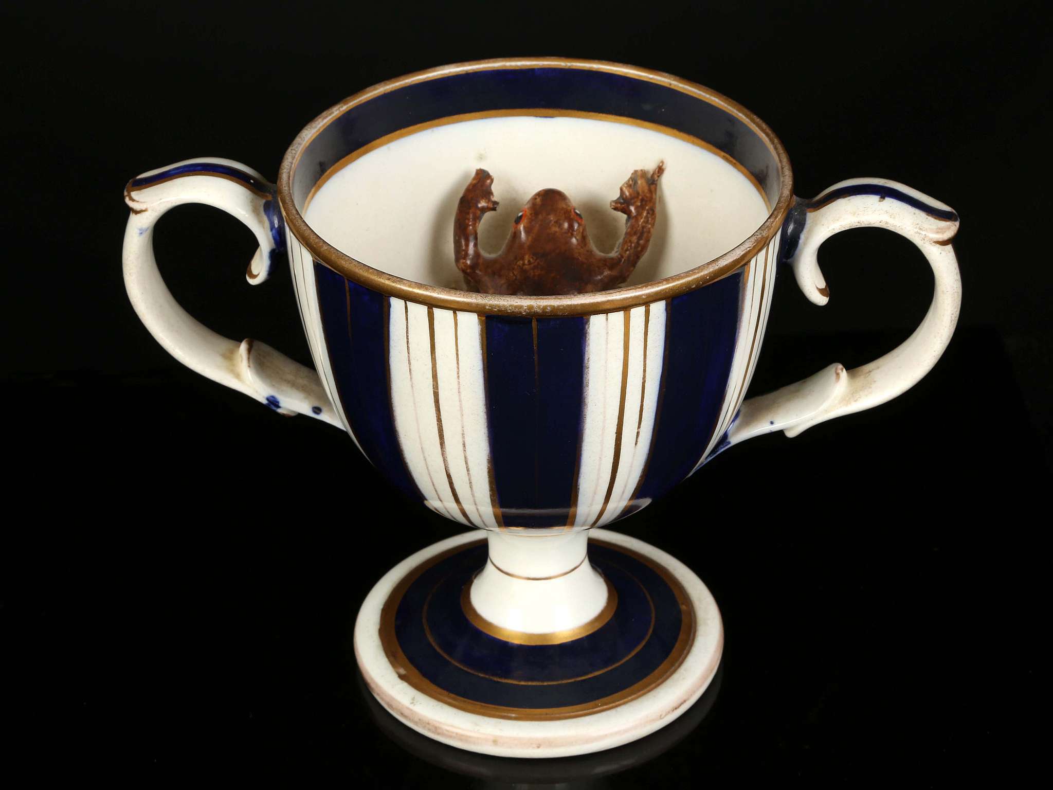 A CHARMING ENGLISH POTTERY LOVING CUP WITH A FROG, circa 1830, the cup ...