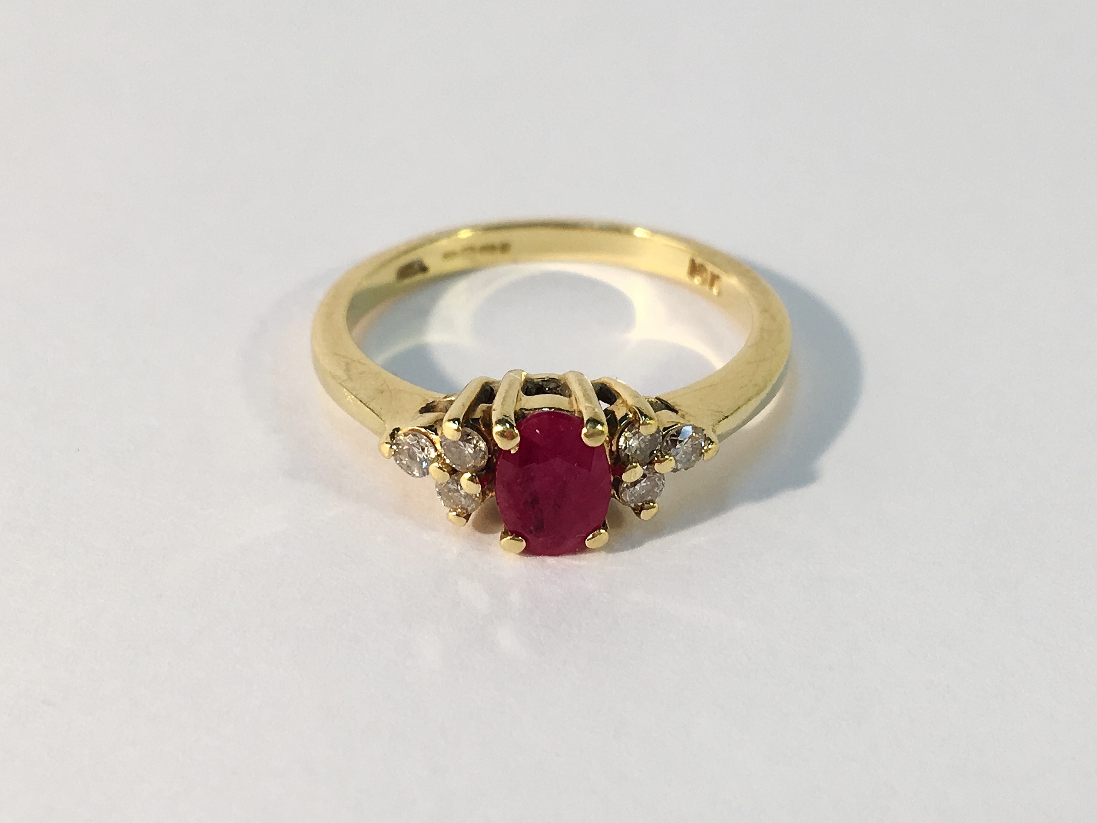 An 18ct gold claw set ring with oval ruby and diamond set shoulders ...