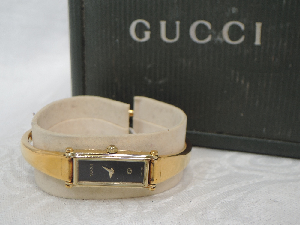 A lady's gold plated bangle watch by Gucci having a plain black ...