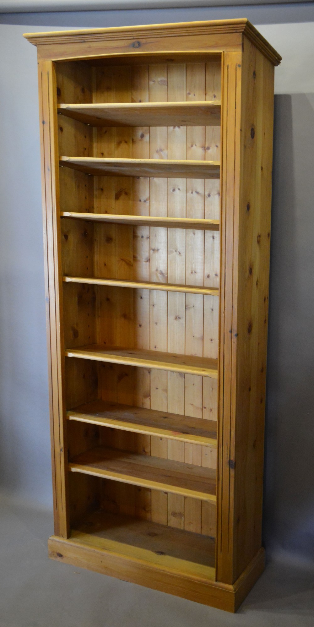 A Tall Pine Bookcase, the moulded top above an arrangement of shelves raised upon a plinth, 87 cm