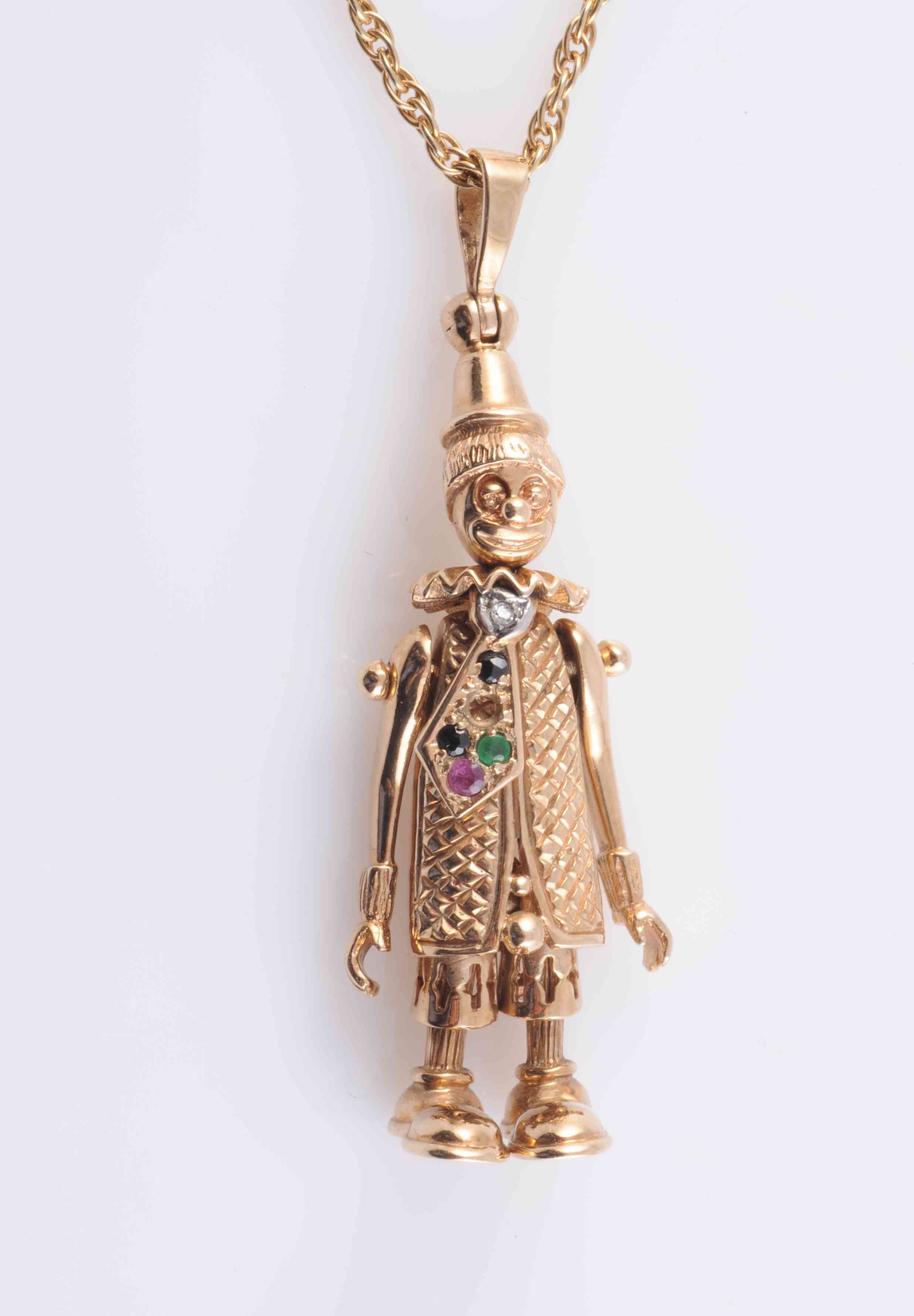 A 9 CARAT GOLD AND JEWELLED ARTICULATED CLOWN PENDANT, on a 9 carat ...