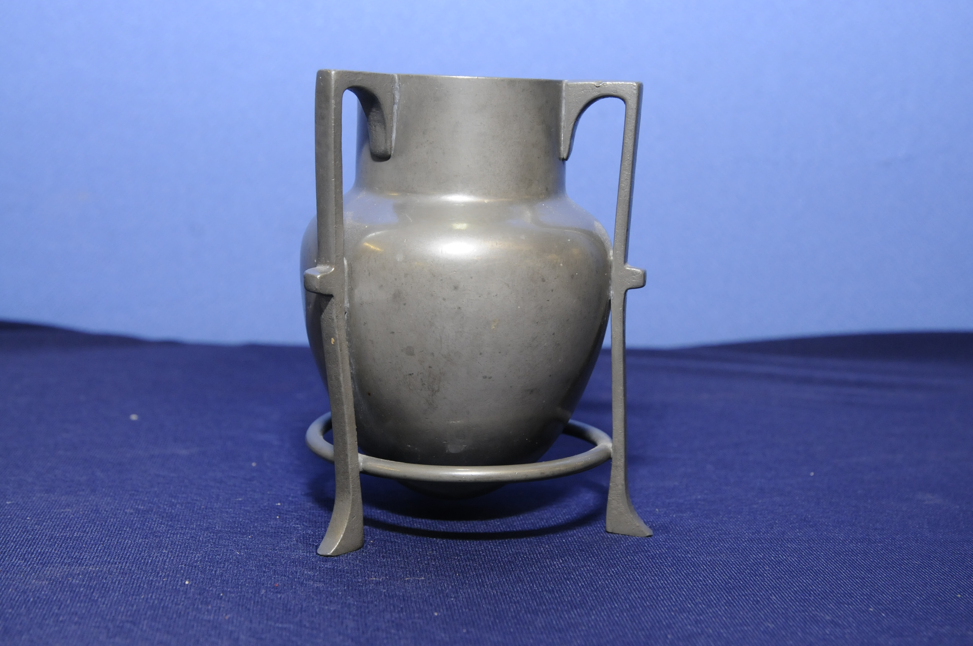 Pewter Arts & Crafts vase on three raised supports, the base marked ...