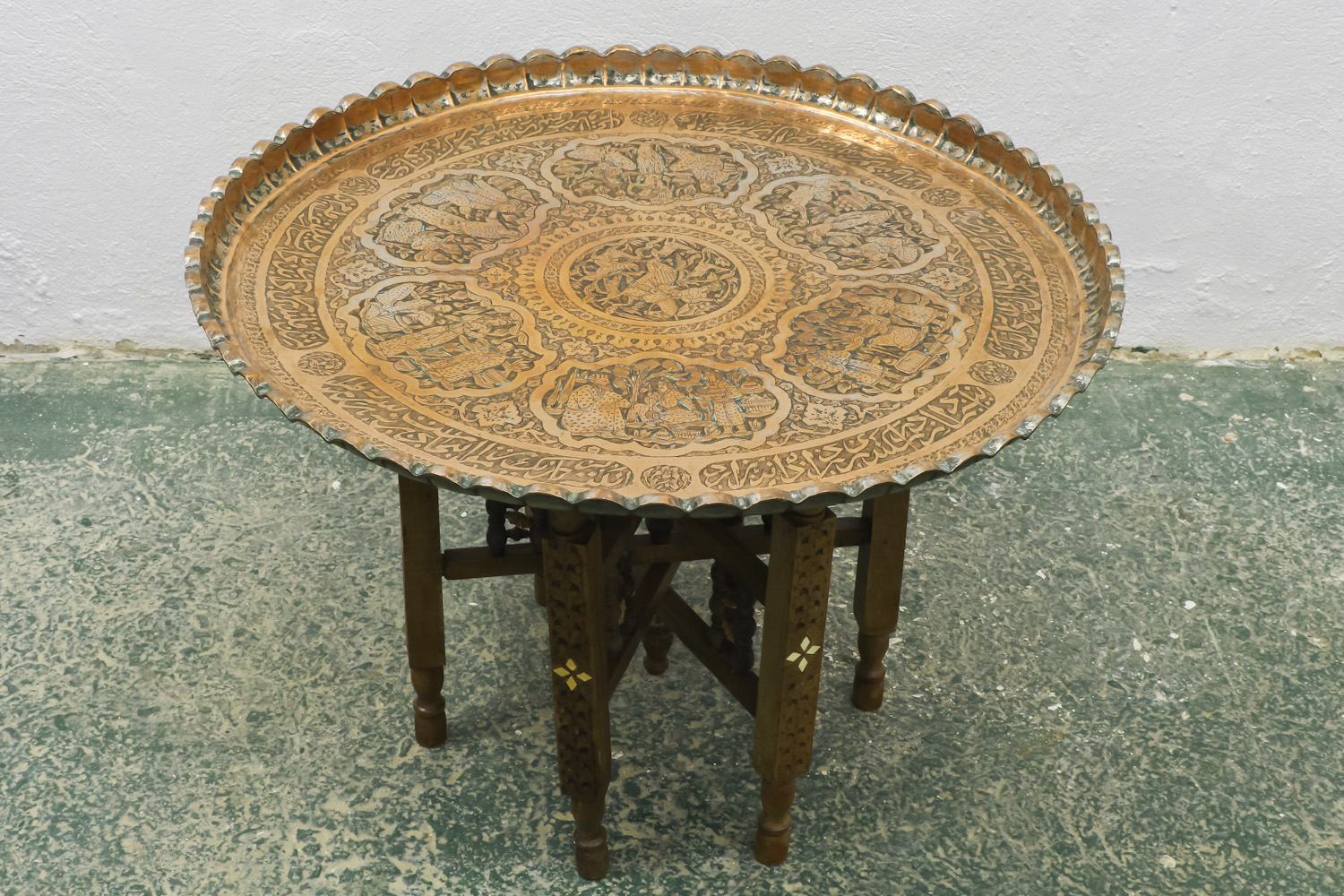 A circular Persian copper tray/table, decorated with scenes within ...