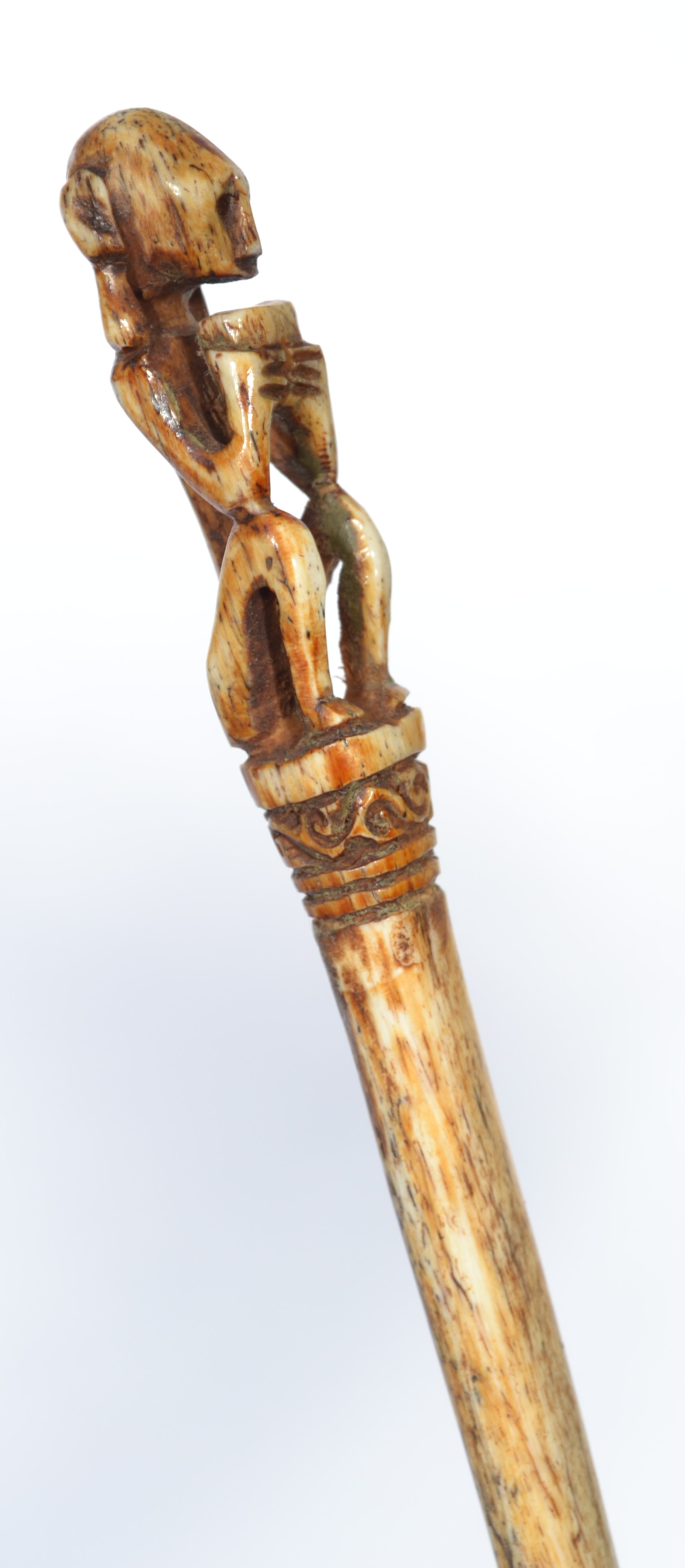 A tribal bone hairpin believed Indonesian, the carved top surmounted ...