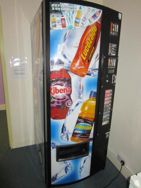 A Lucozade, Coke, Orange Drinks Vending Machine.