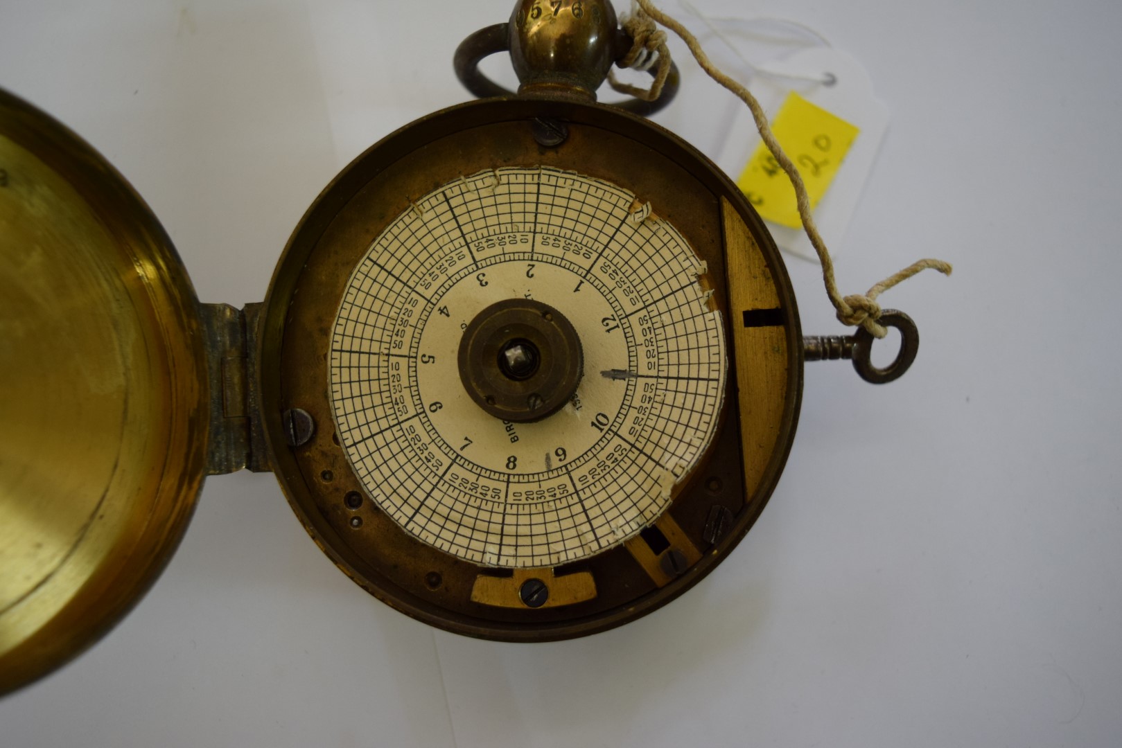 An antique brass meter, with paper dial.