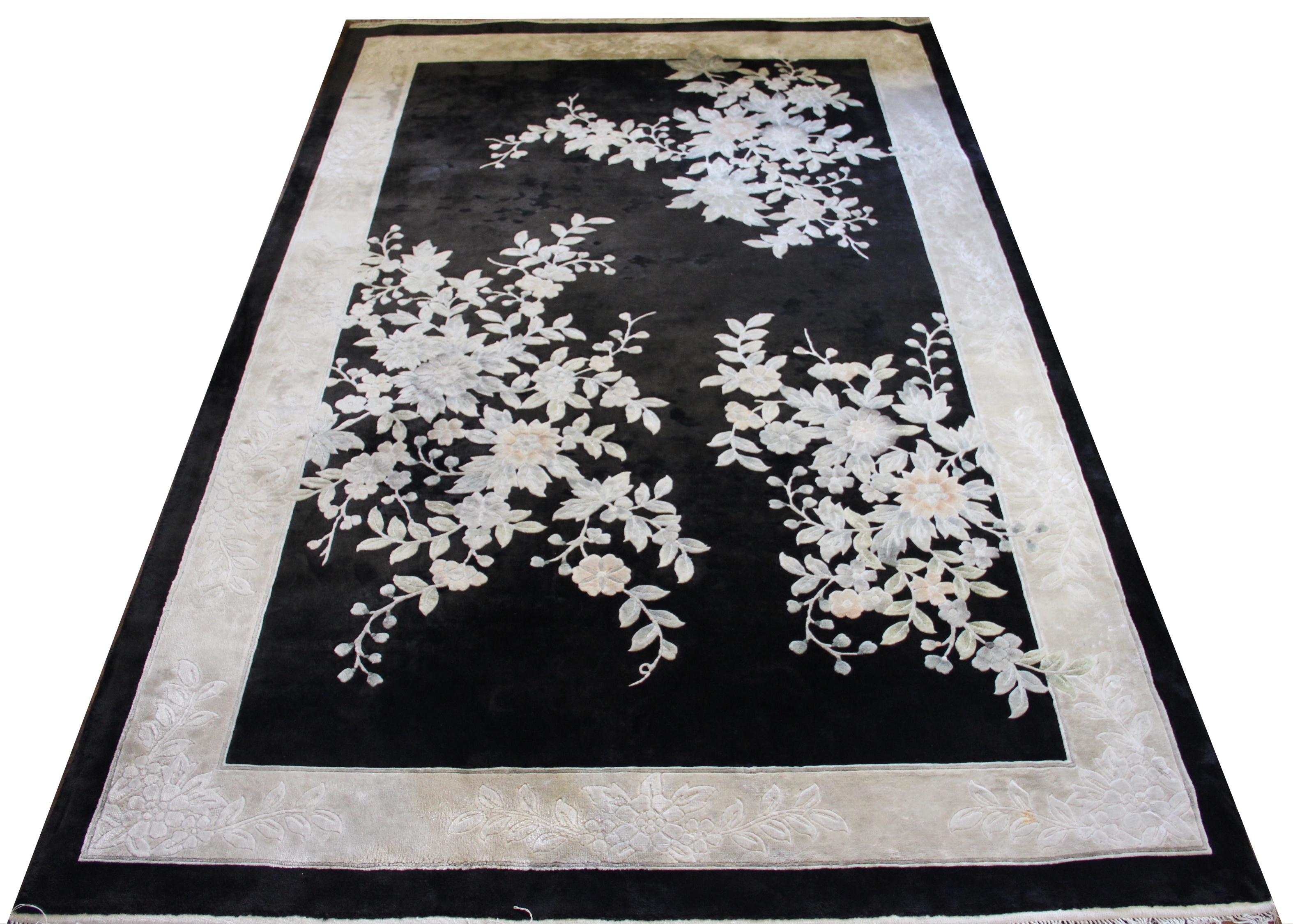 A Chinese rug, decorated with three floral sprays against a black ...