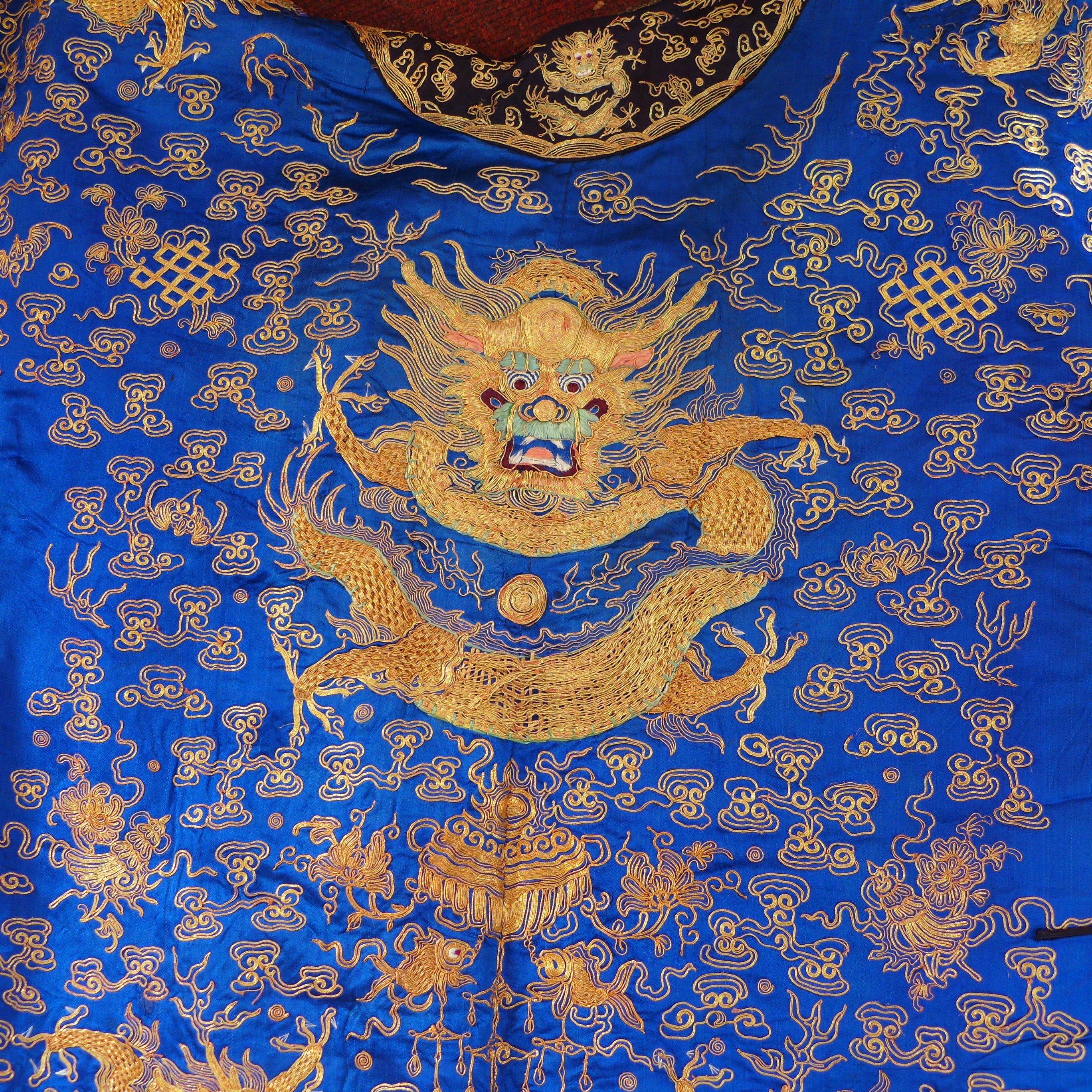 A Chinese silk ceremonial garment with embroidered dragons on a blue ground
