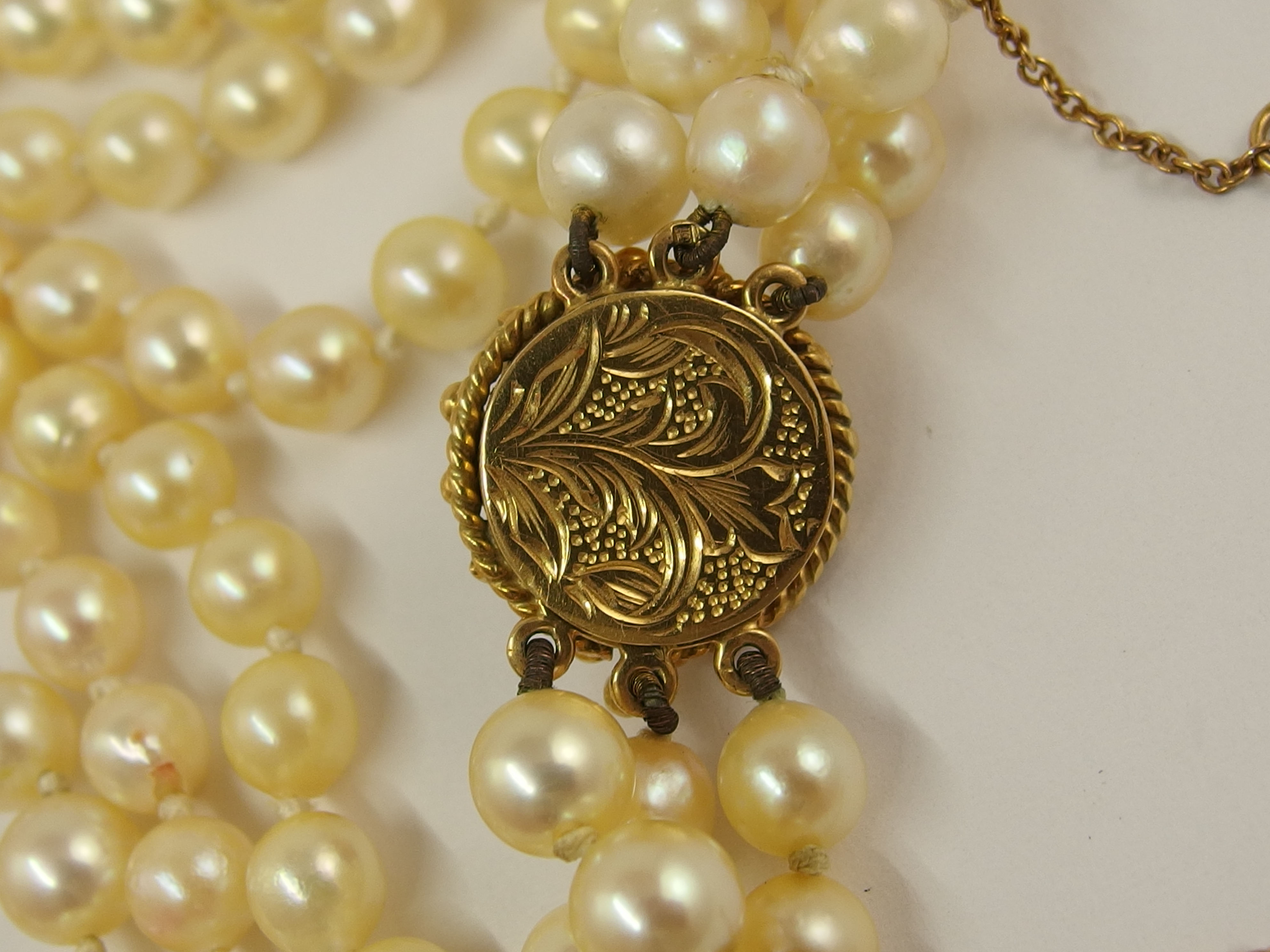 A triple string of pearls with a garnet and pearl clasp the gold ...