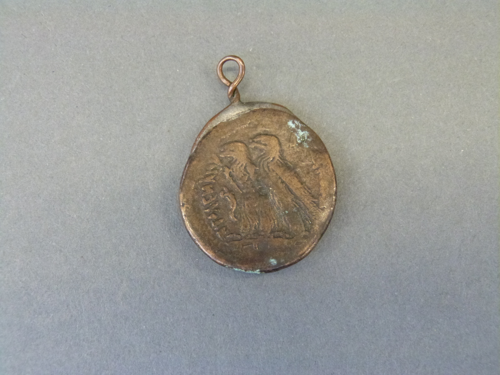 Ancient bronze oval coin, possibly Greek, depicting two perched eagles ...