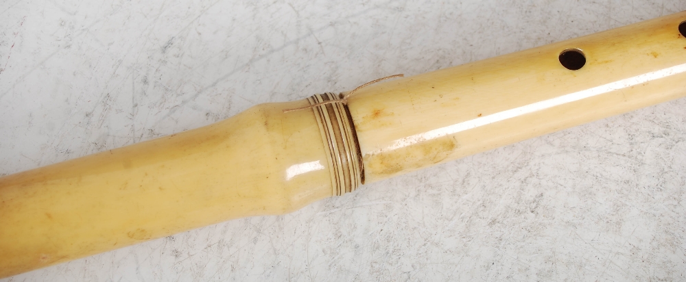 A 19th century ivory one-keyed flute, formed in four sections, 59cm long.
