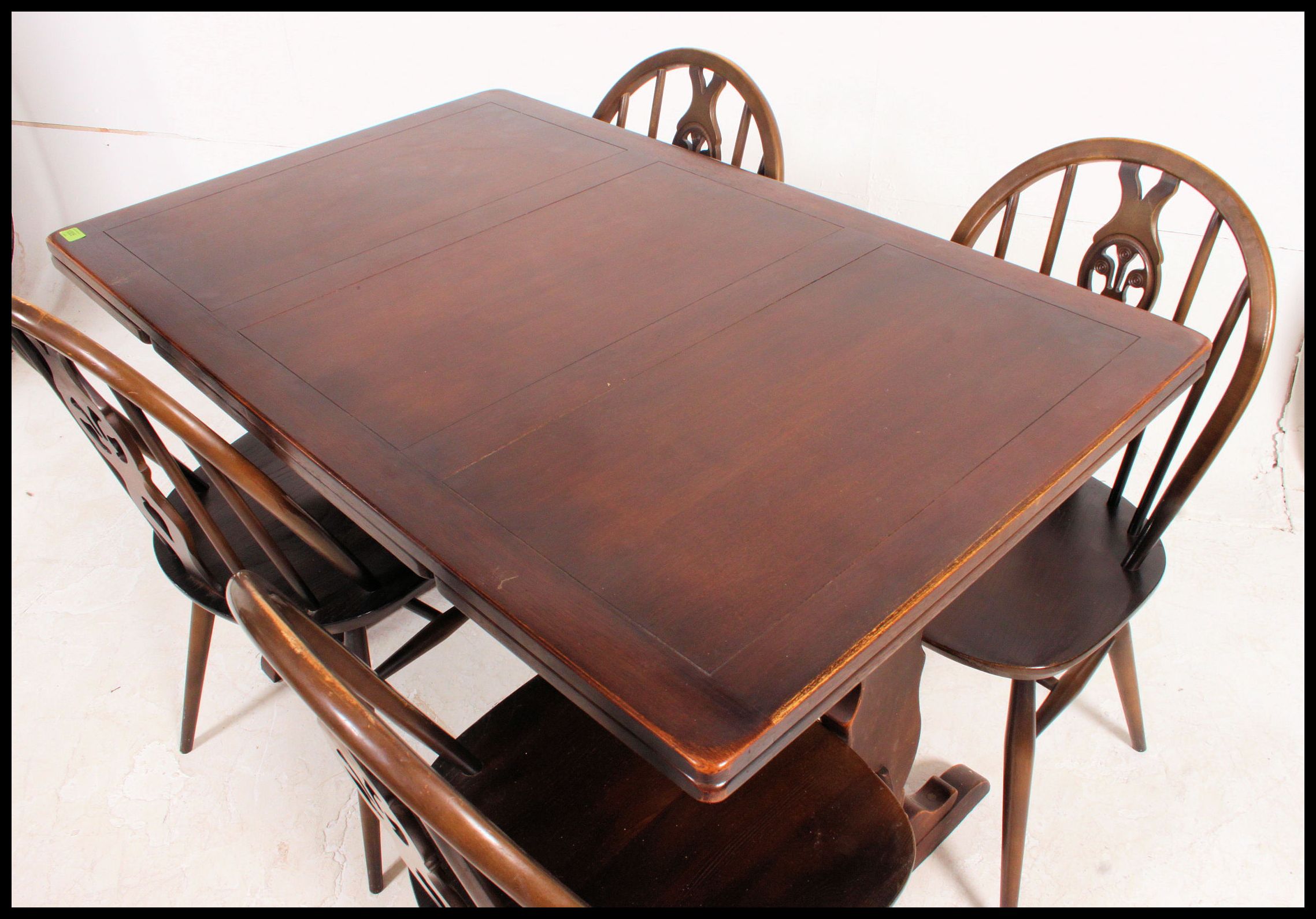 An early Ercol dark wood draw leaf refectory dining table together with ...