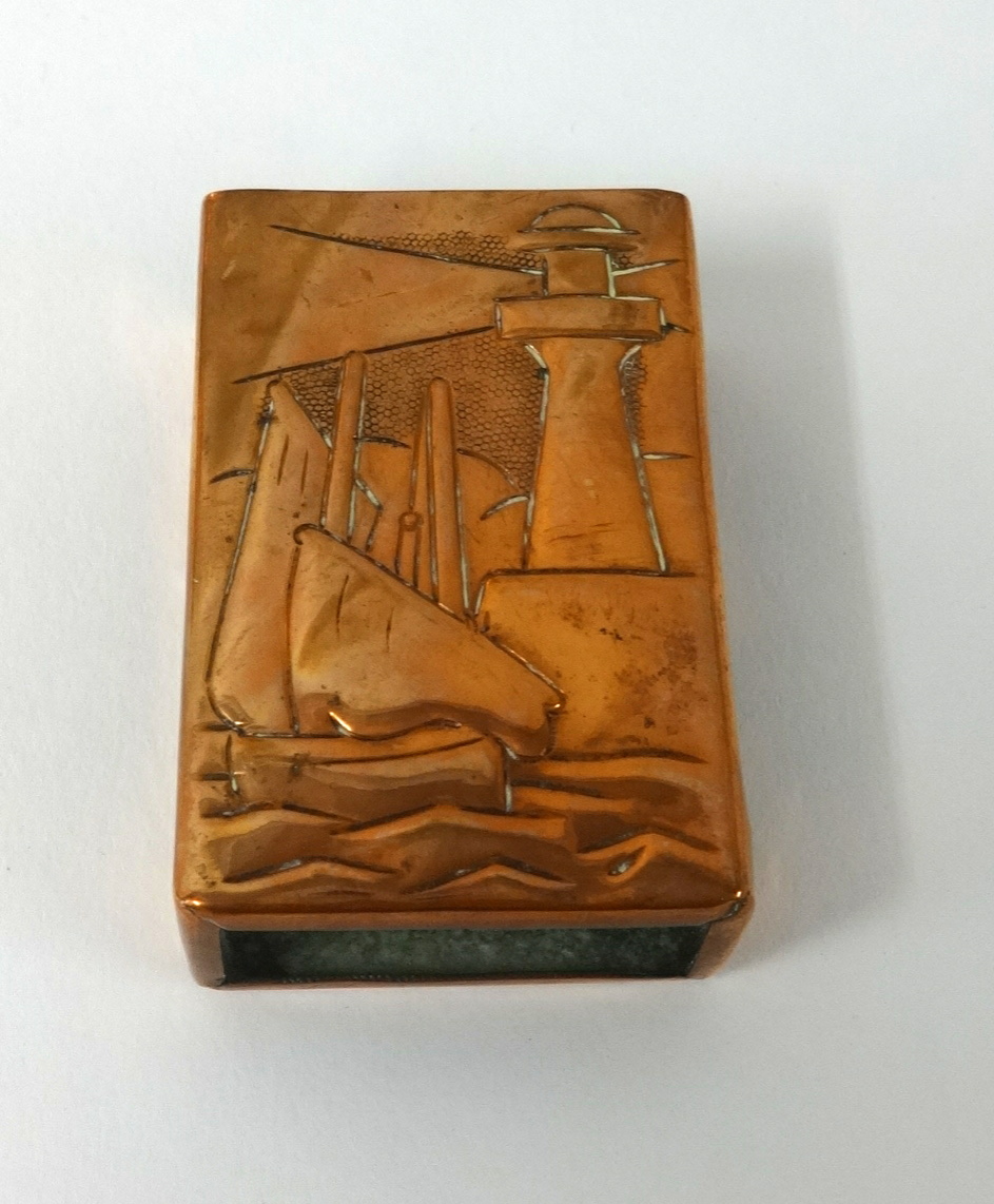 A Newlyn copper matchbox holder embossed with lighthouse and sailing ...