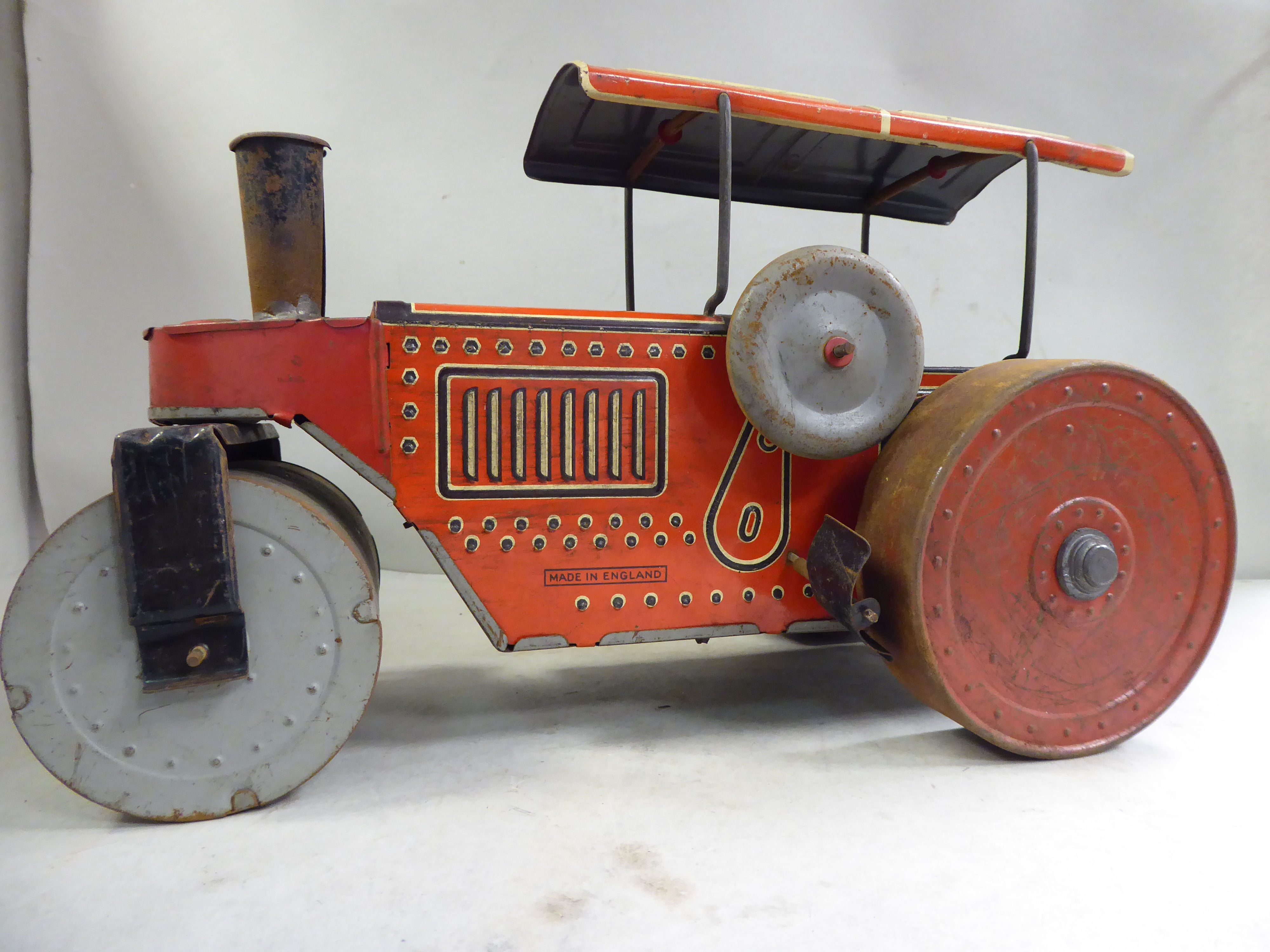 A 1930s red and grey painted, tinplate toy steamroller with a steering ...