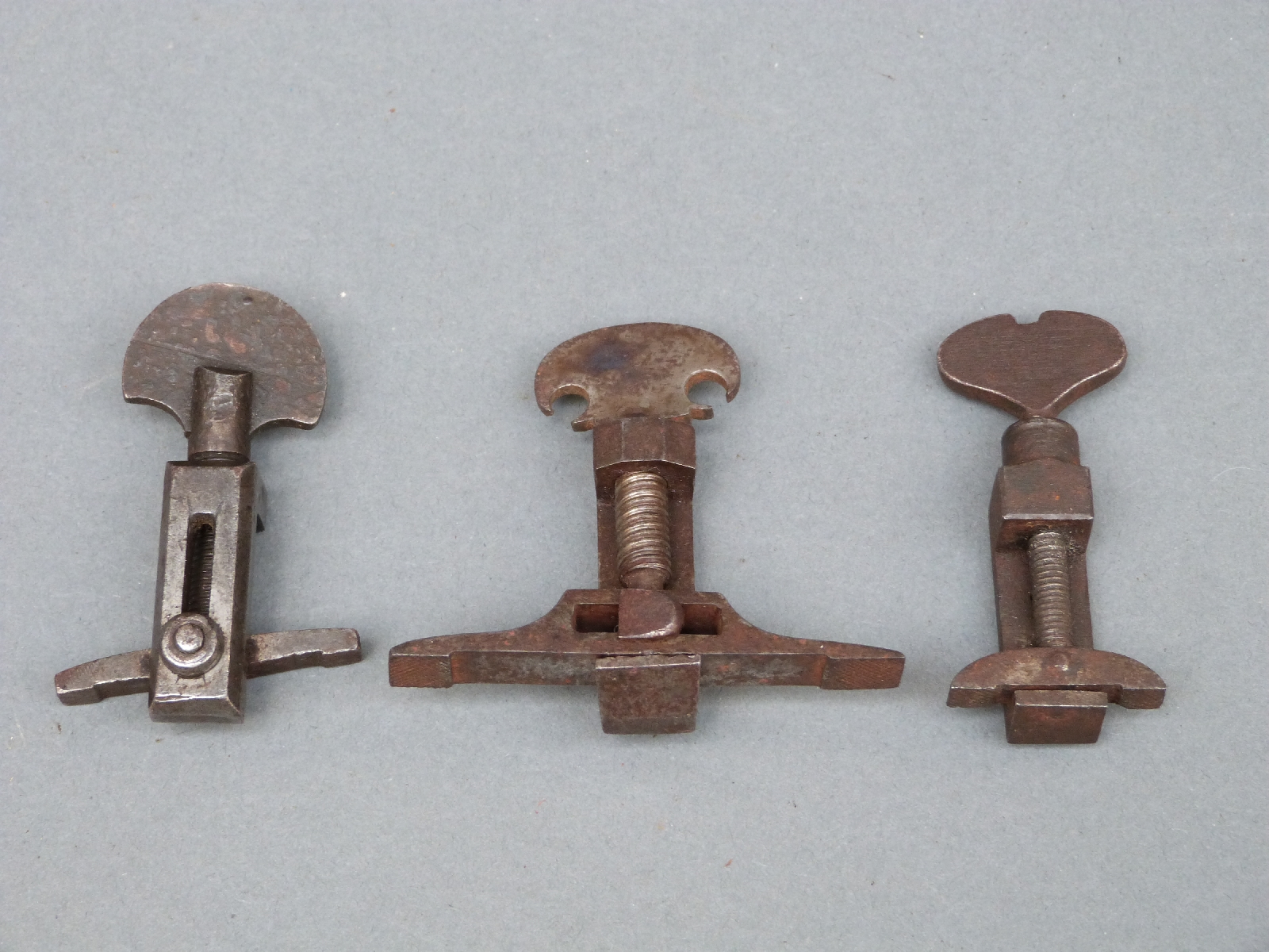 Three flintlock gun mainspring clamps, one with pierced grip.