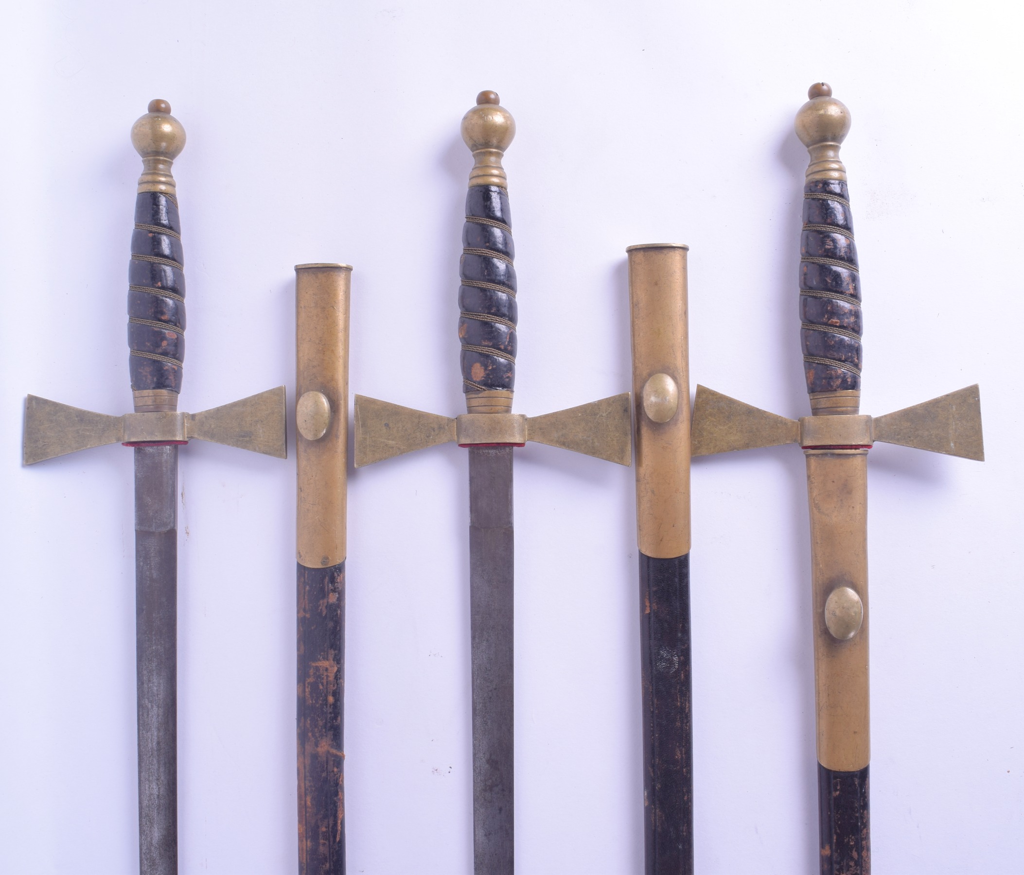 A SET OF THREE ANTIQUE BRASS HANDLED SWORDS with cross type terminal ...