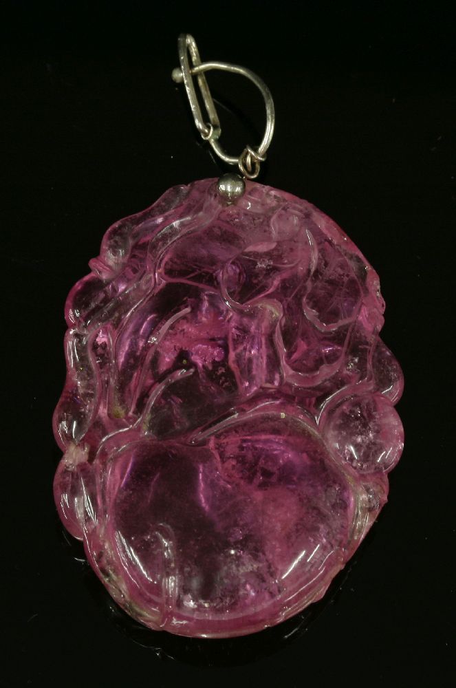 A Chinese carved pink tourmaline pendant,depicting peaches and foliage ...