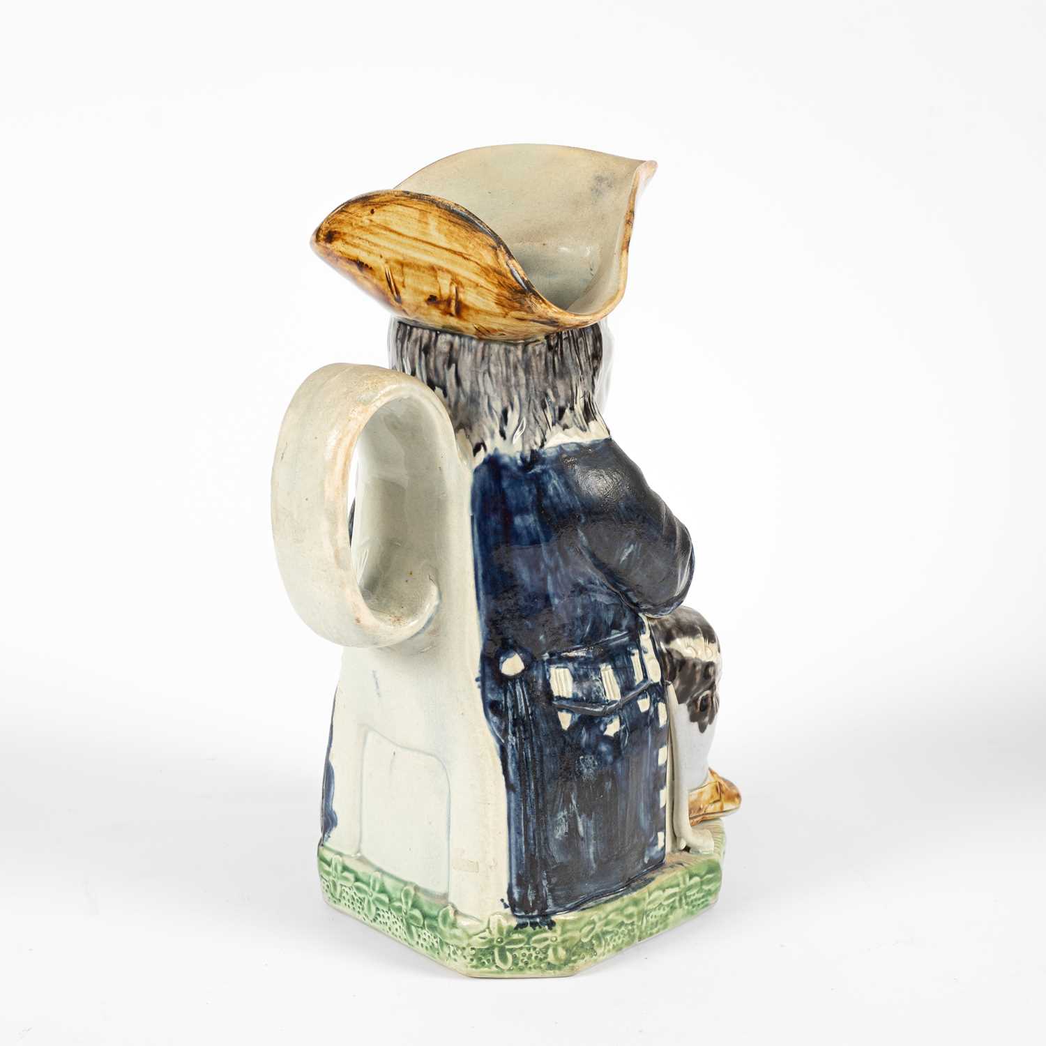 A Wood type Toby jug, wearing a blue coat and on a green plinth with ...