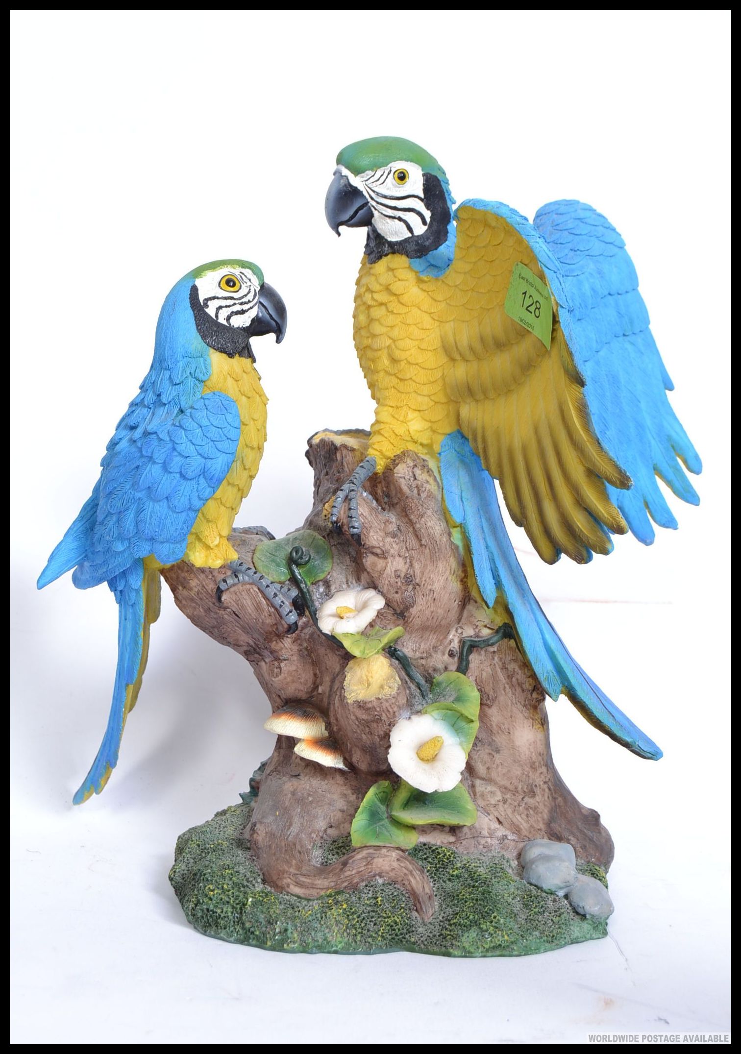 A highly detailed resin parrot figurine group perched atop a tree trunk ...