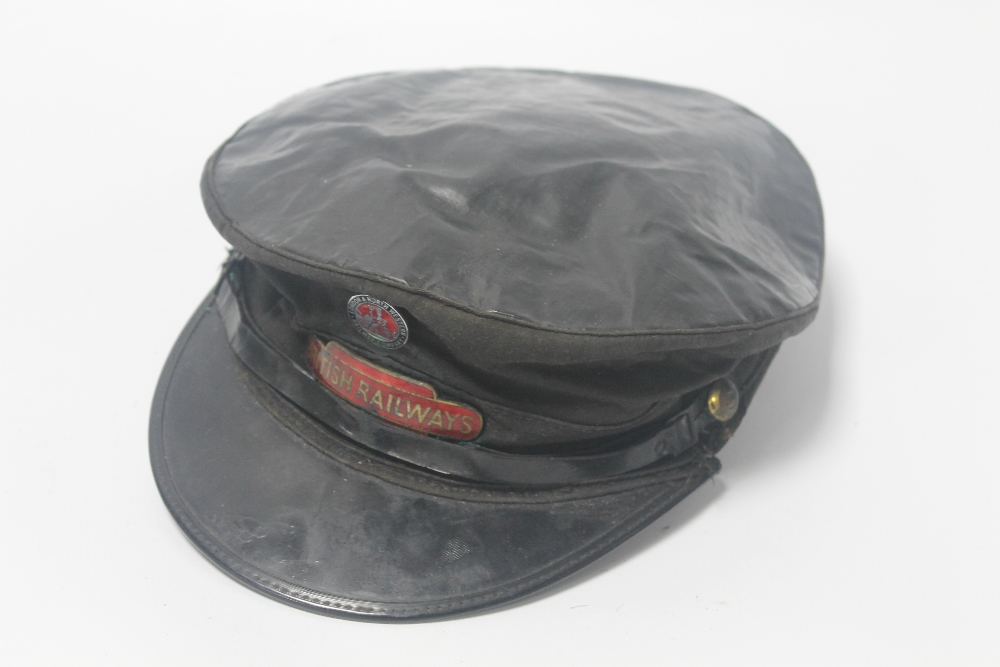 A BRITISH RAILWAYS FIREMAN'S HAT, with red enamel cap badge and an ...