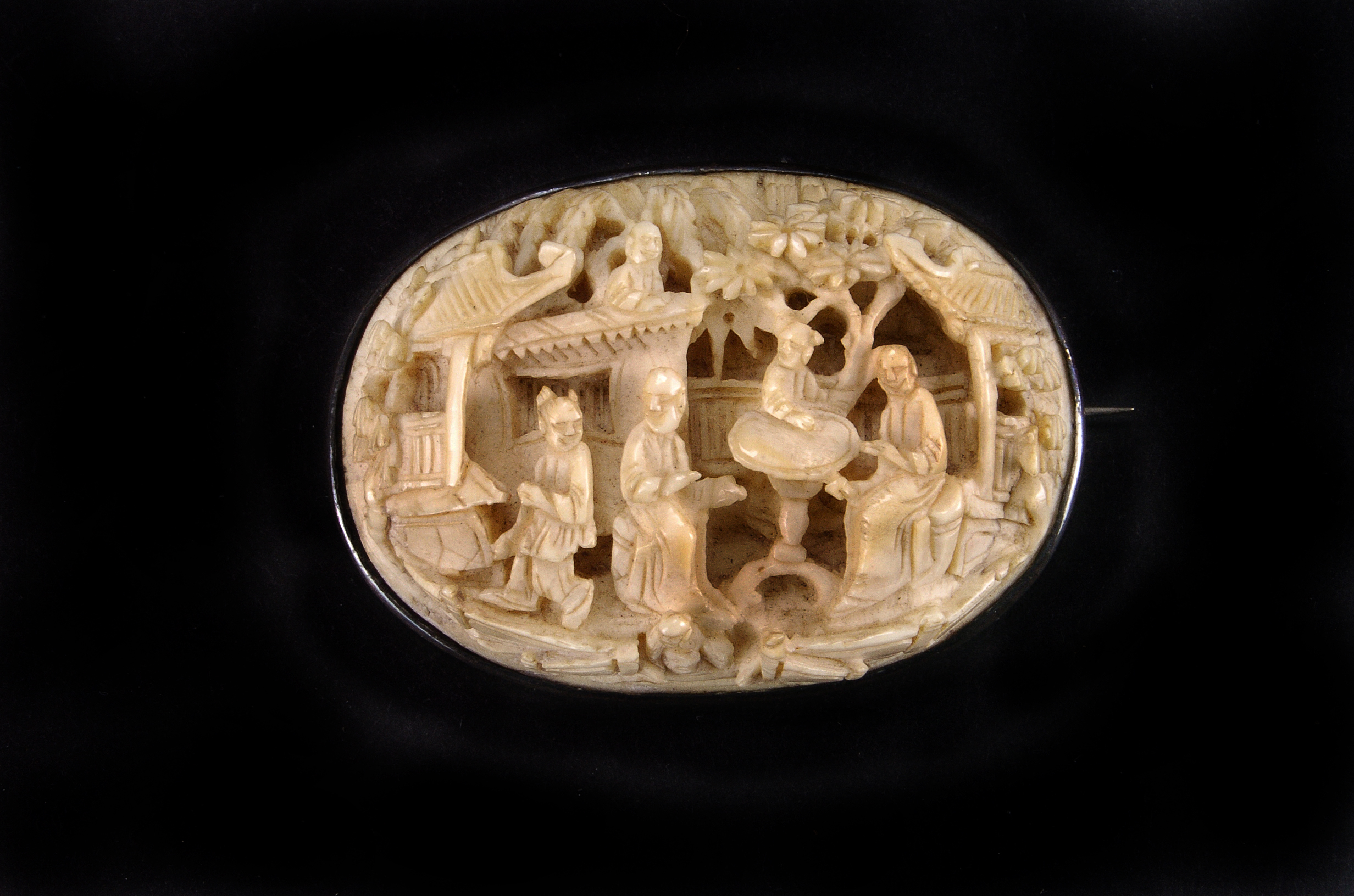 An Edwardian period Chinese carved ivory brooch, the oval finely carved ...