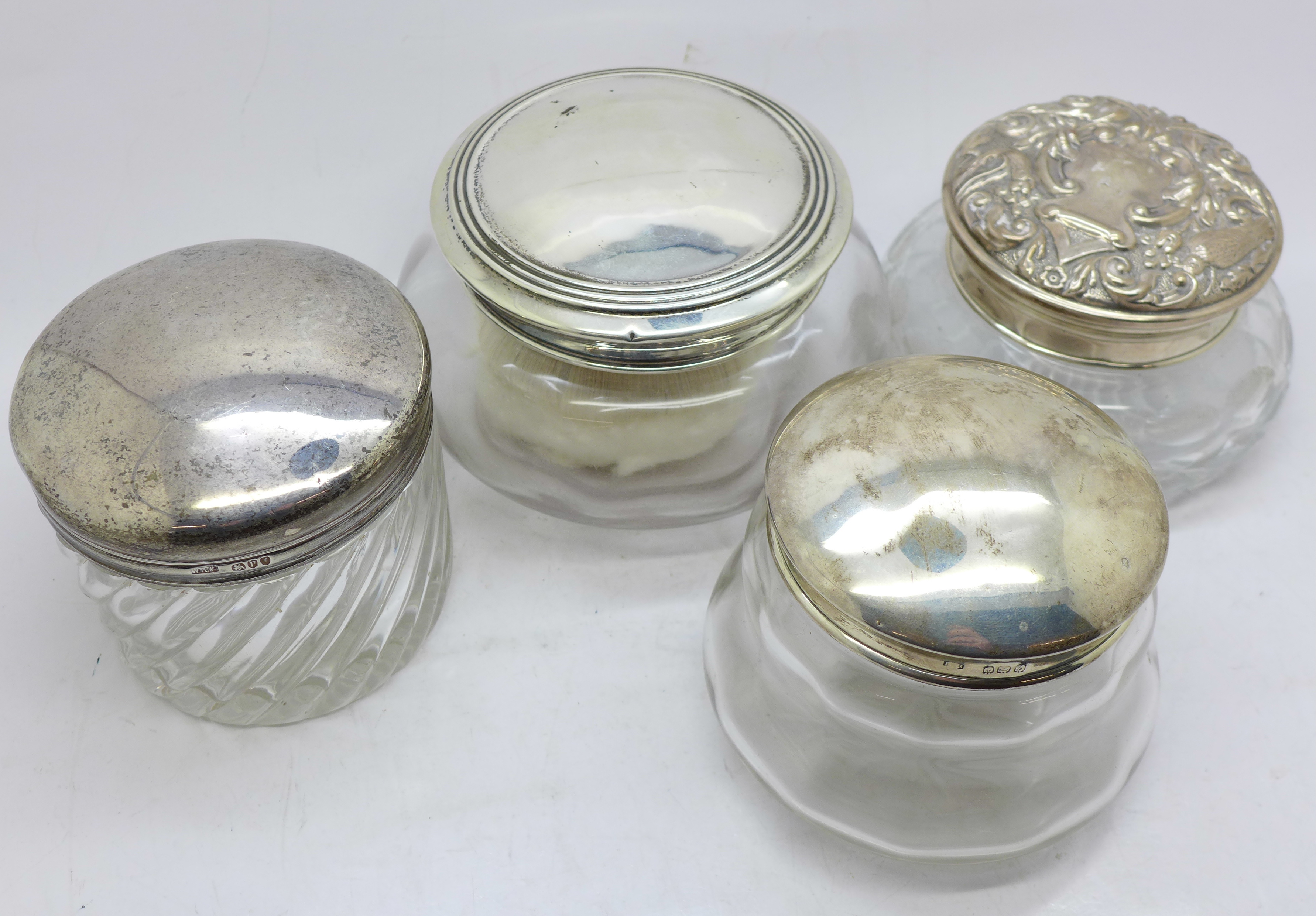 Four silver topped glass jars, one rim chipped