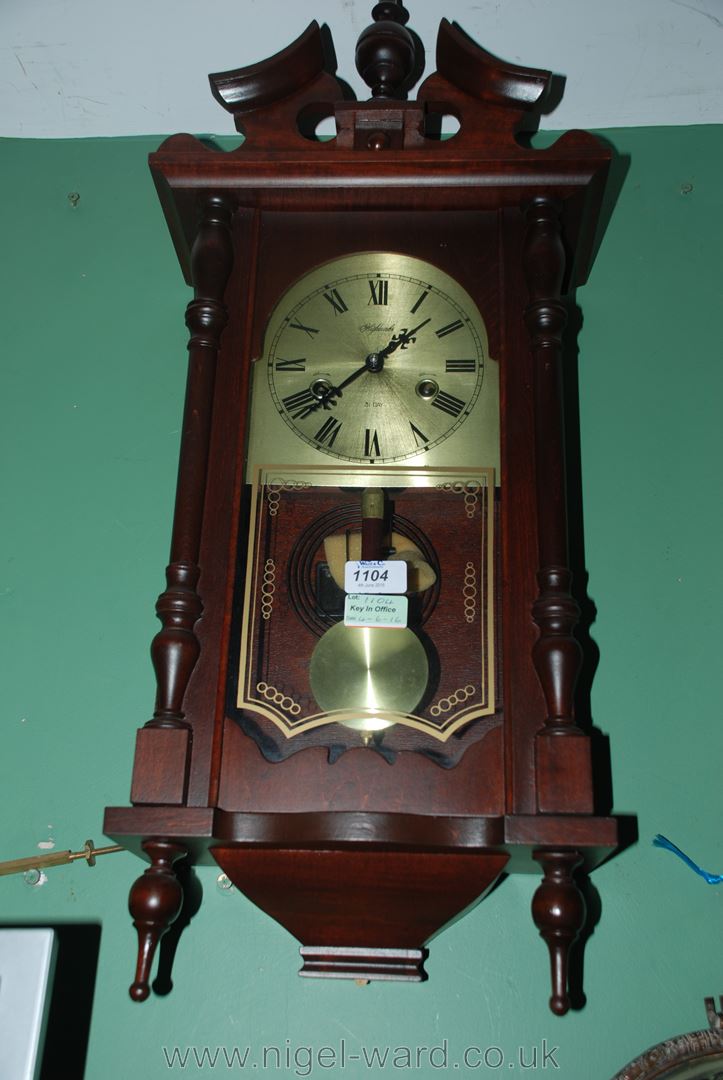 A wooden cased 31 day Wall Clock, by Highlands, with key and pendulum.