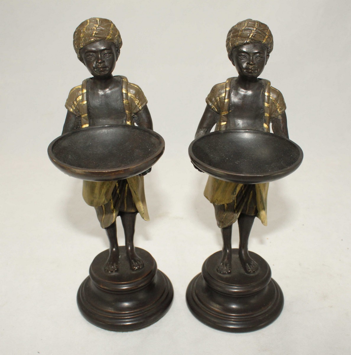 A pair of Blackamore bronze figures holding bowls, with gilt decoration ...