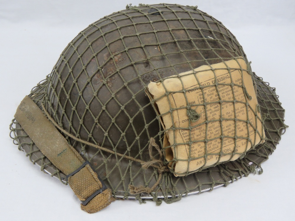 A WWII British Military 'Tommy' helmet with camo netting and emergency ...