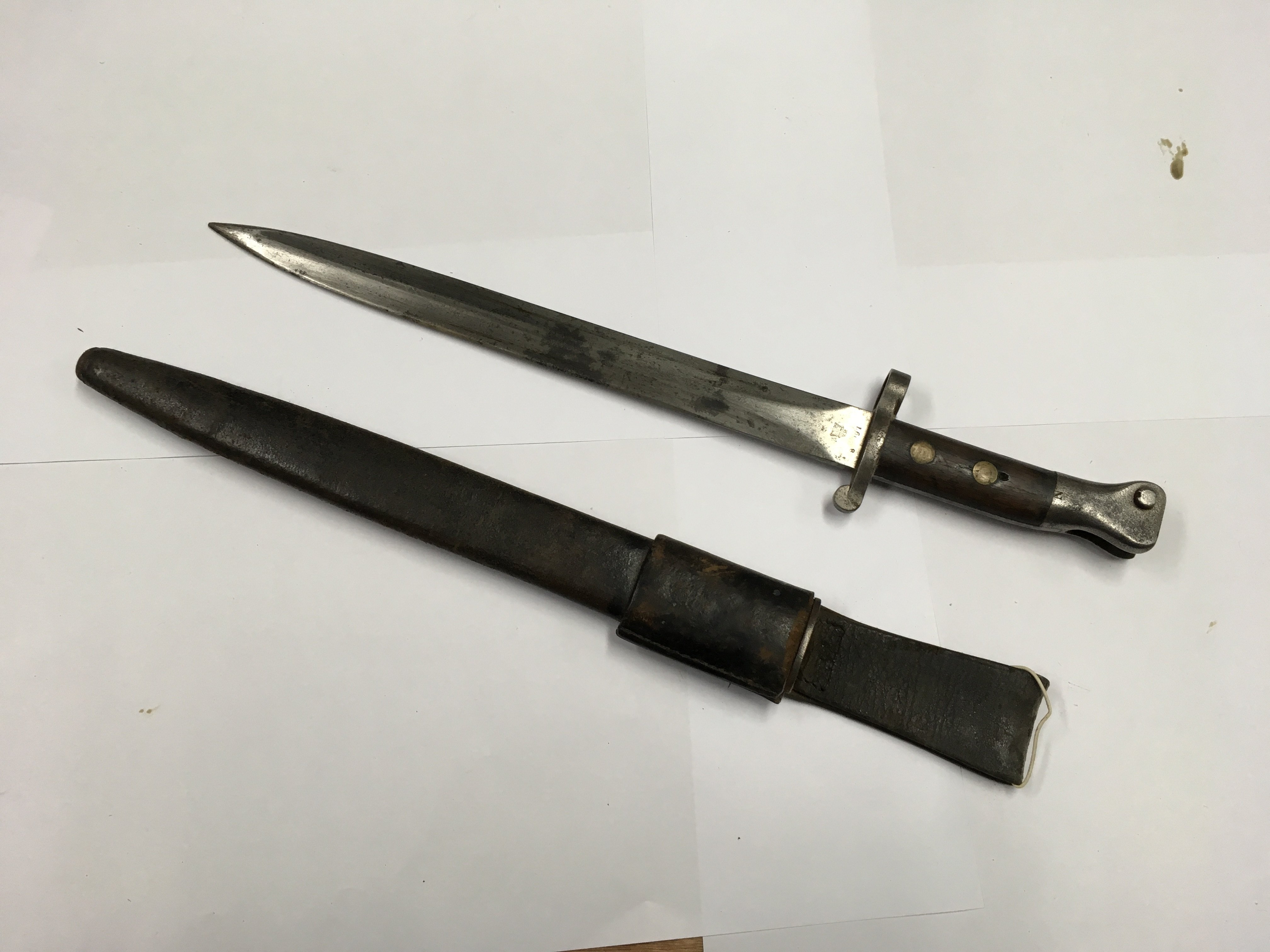 A British Pattern 1888 Mk.1 bayonet with a leather scabbard.