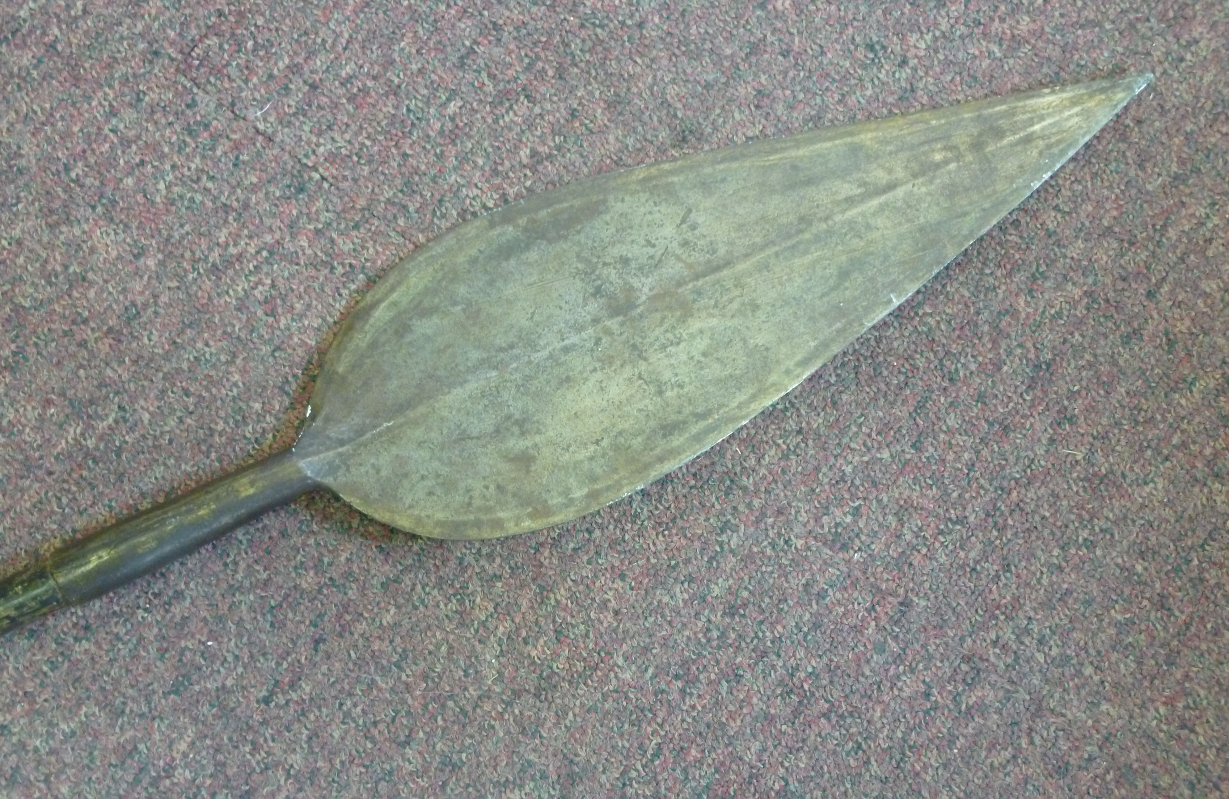 A native spear, the broad flattened steel head on a wooden shaft 70''L ...