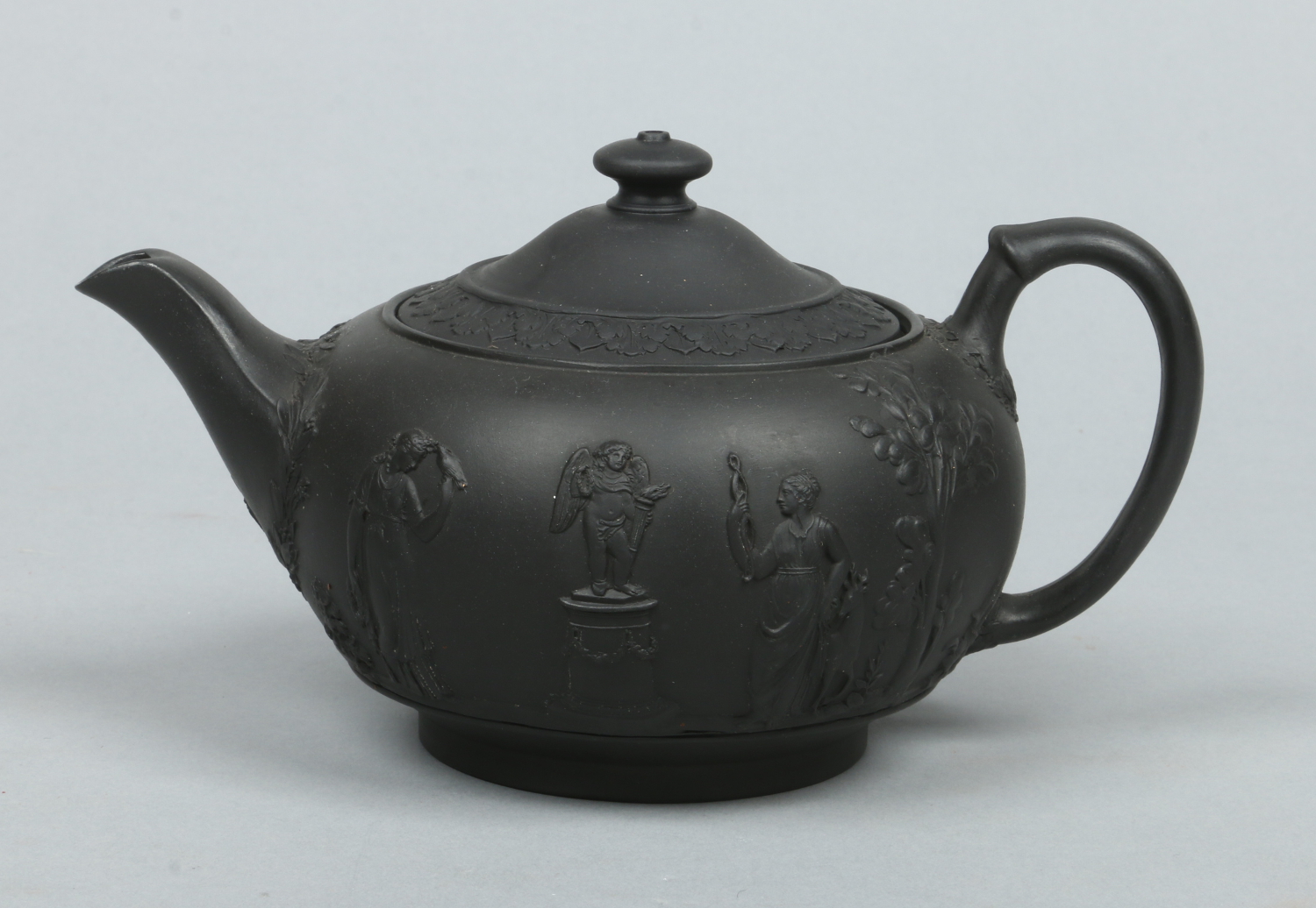 A Victorian Wedgwood black basalt teapot and cover. Moulded in relief ...