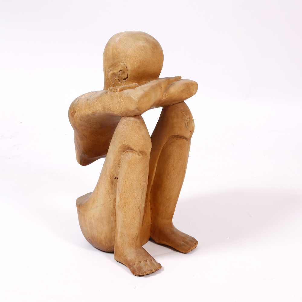 A CARVED WOODEN SCULPTURE of a crouching figure resting their head on ...