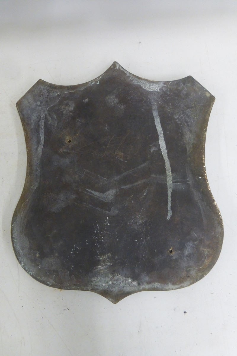 A shield shaped brass plaque, the design divided into four quarters ...