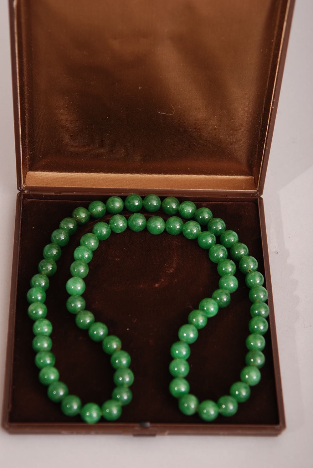 C20th Chinese emperor-green jade necklace composed of a strand of round ...