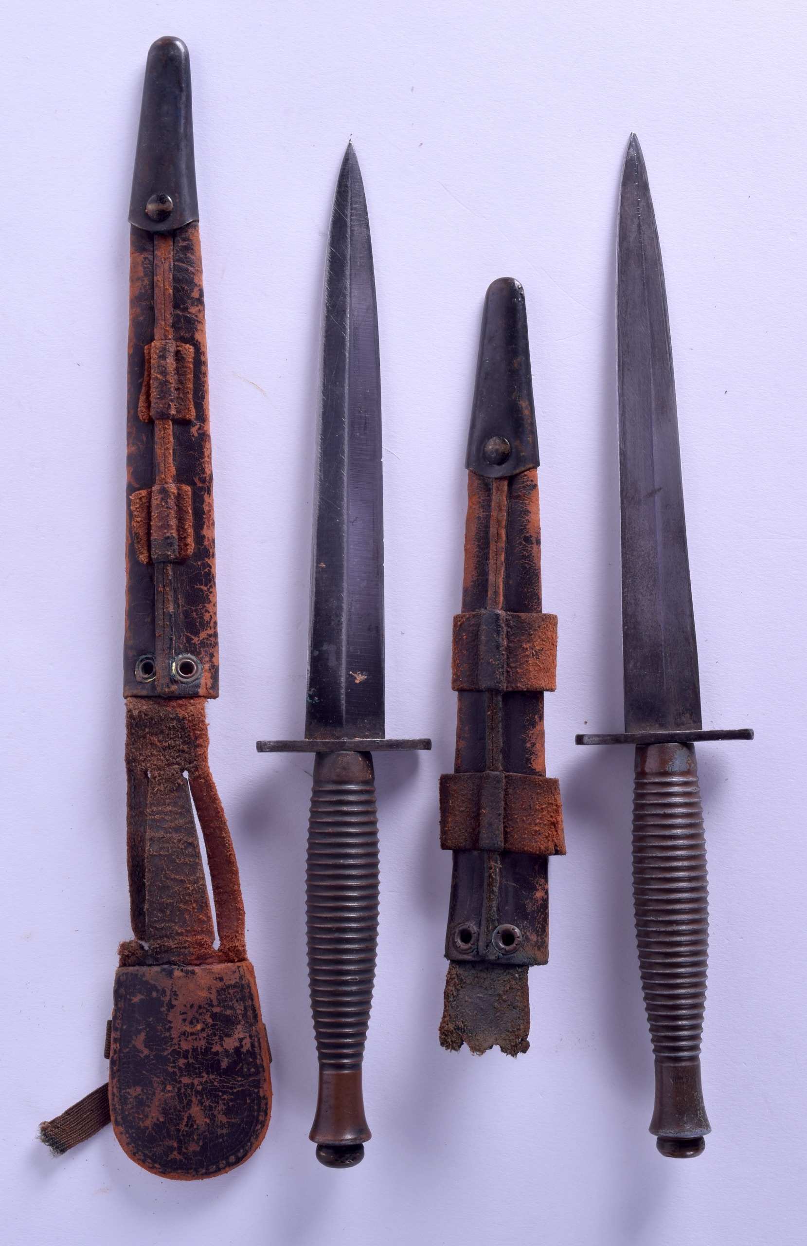 A PAIR OF EARLY 20TH CENTURY MILITARY DAGGERS within leather sheaths ...