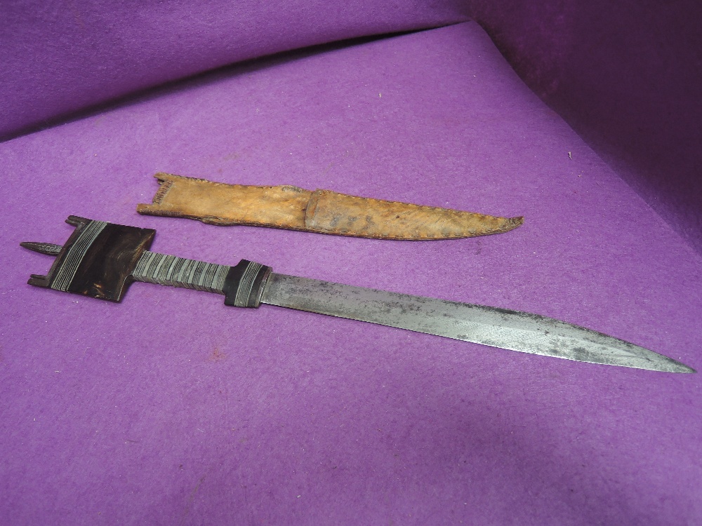 A Nigerian short sword with decorated handle and leather scabbard